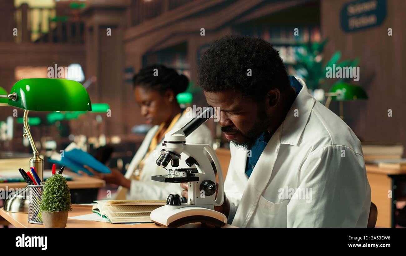 Male student researching viruses during a microscope analysis and ...