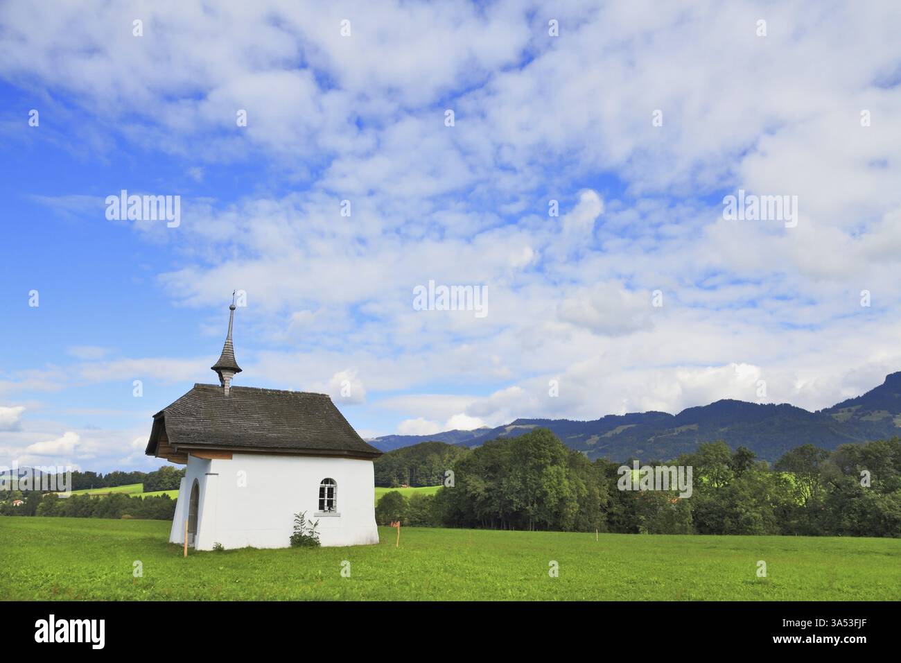 Small rural chapel on a green meadow crowned picturesque cross. Bright ...