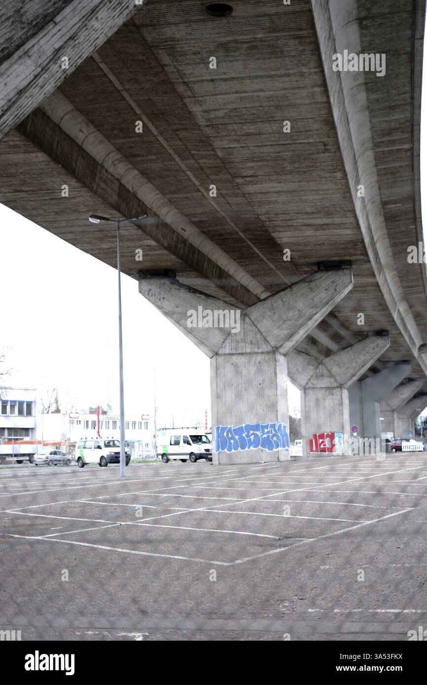 A fenced-off car park in the city under a bridge with lanes on a main ...