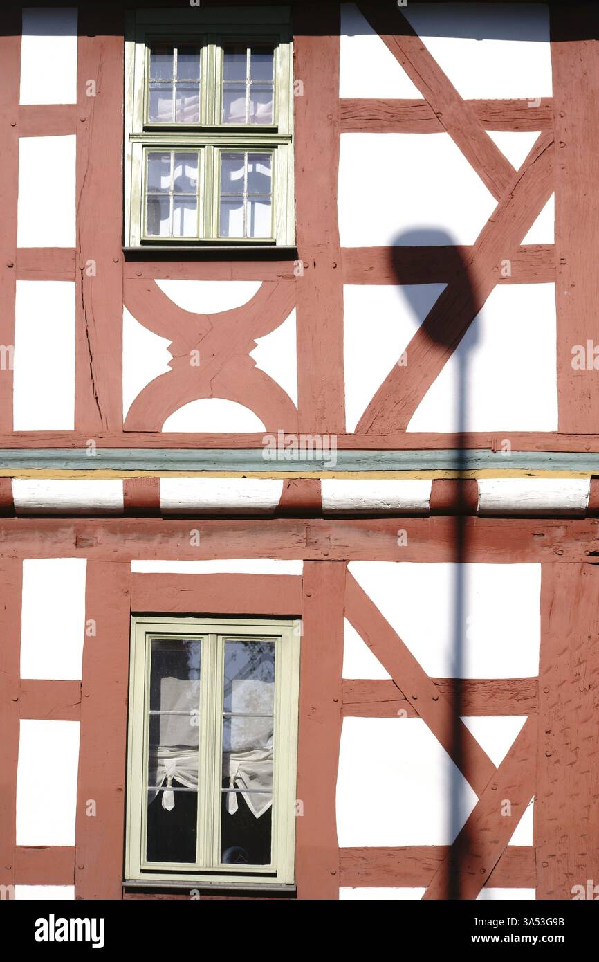 A street lamp casts a shadow on the light-coloured facade and beam ...