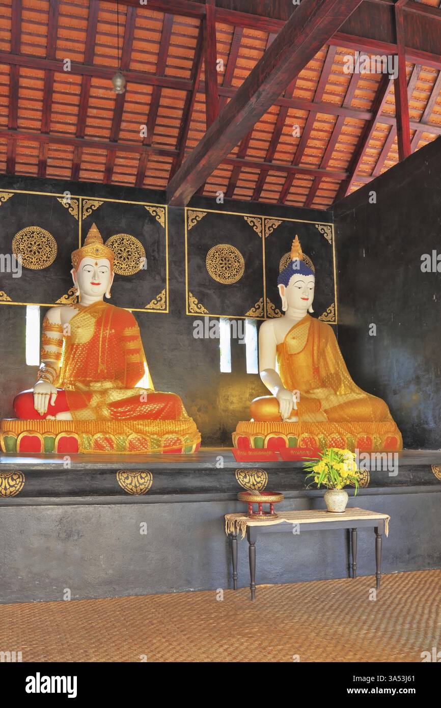 Two statues of the Buddha under a canopy. The statues dressed in gilded ...