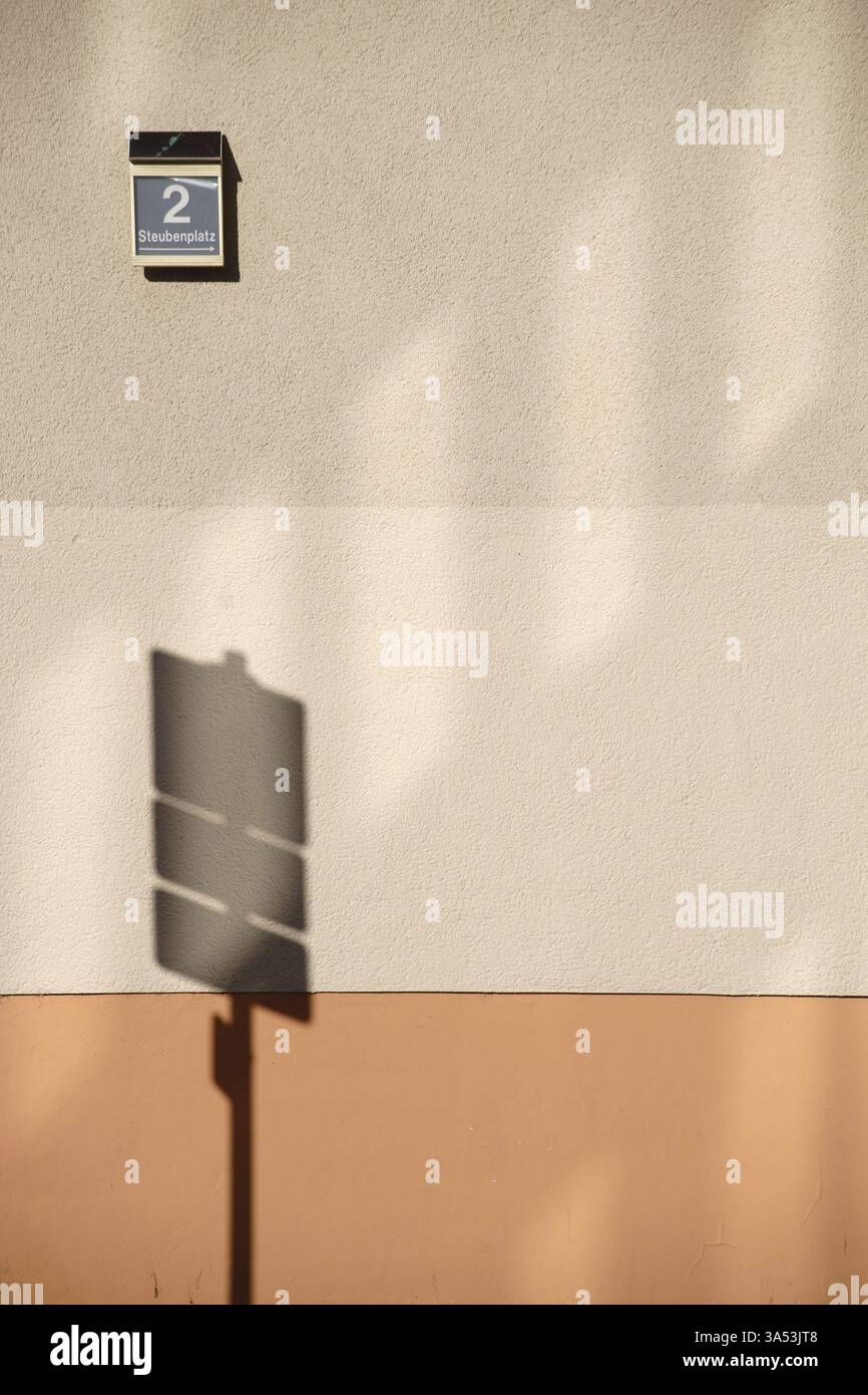 A traffic sign casts an abstract shadow on a house wall with a house ...