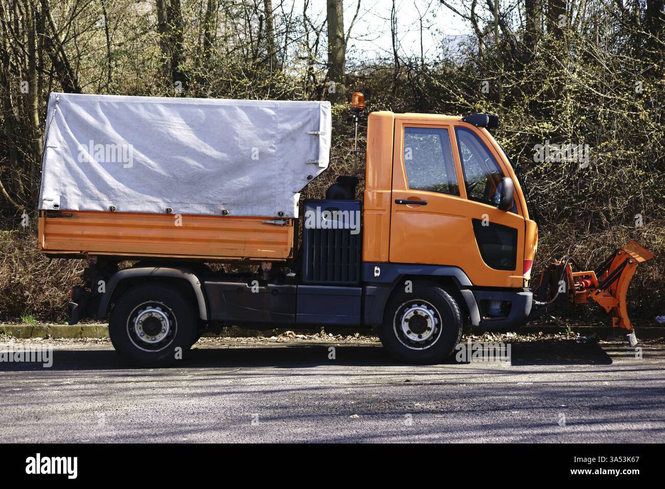 The side view of a small clearing vehicle with plough and loading area ...
