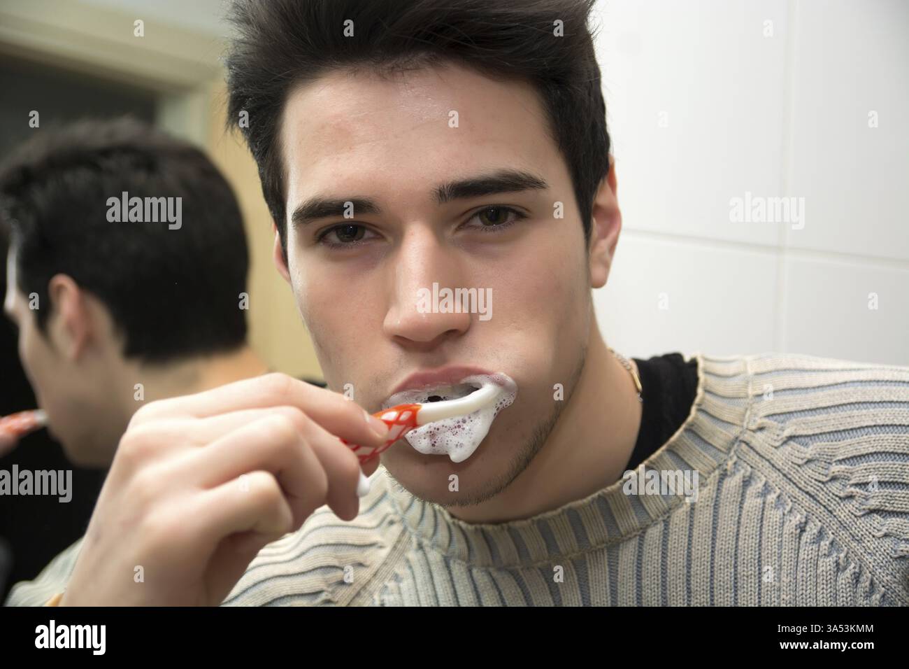 Headshot of attractive young man brushing teeth with toothbrush ...
