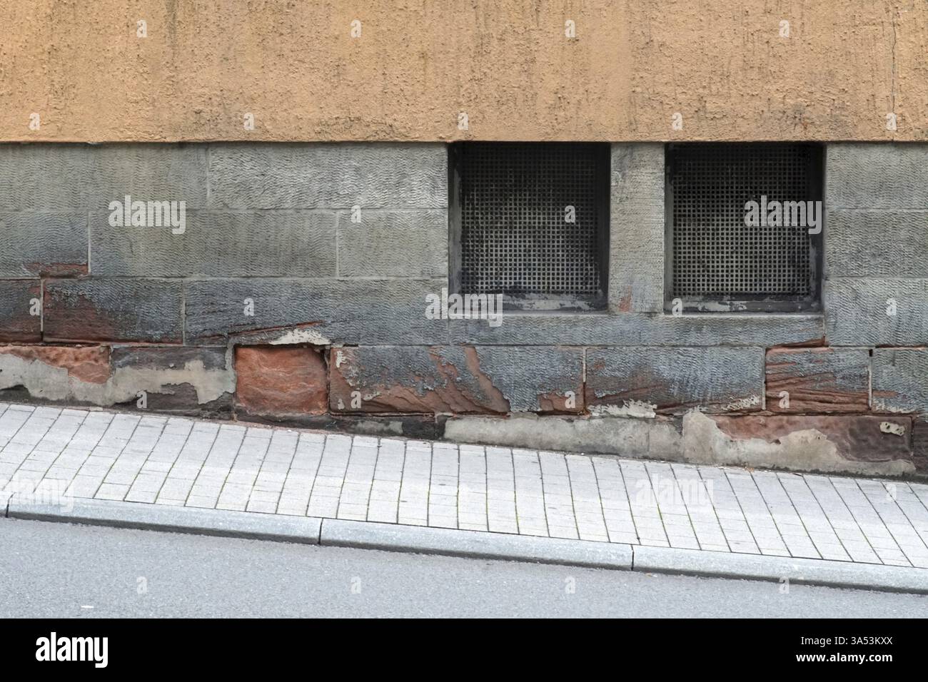 An old residential building with basement windows on a pavement with a ...