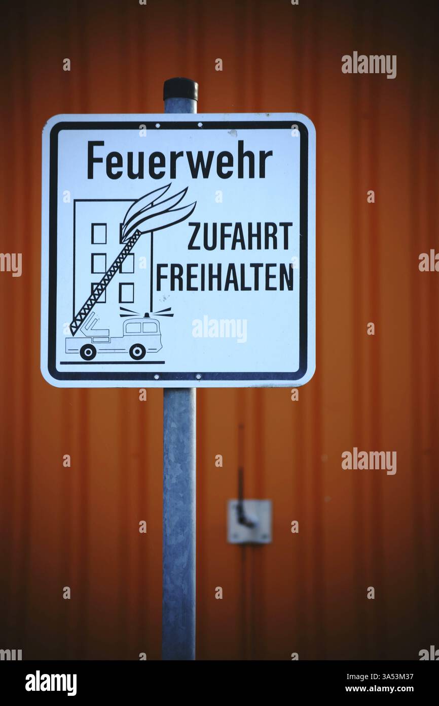 A sign for a fire service access road in front of an orange facade ...