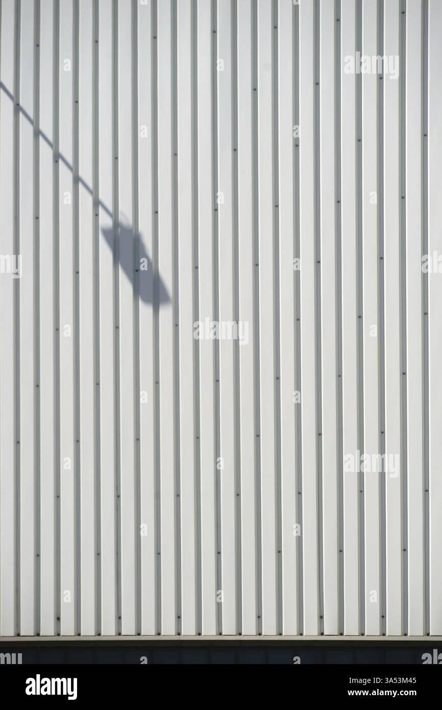 A close-up of a facade made of corrugated iron panels with a shadow of ...
