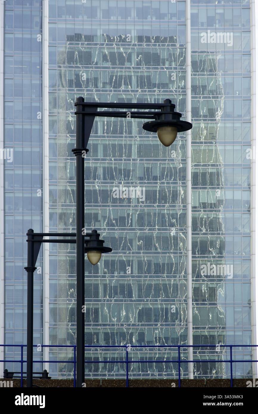 Street lamps stand in front of a bridge and the glass facade of a ...