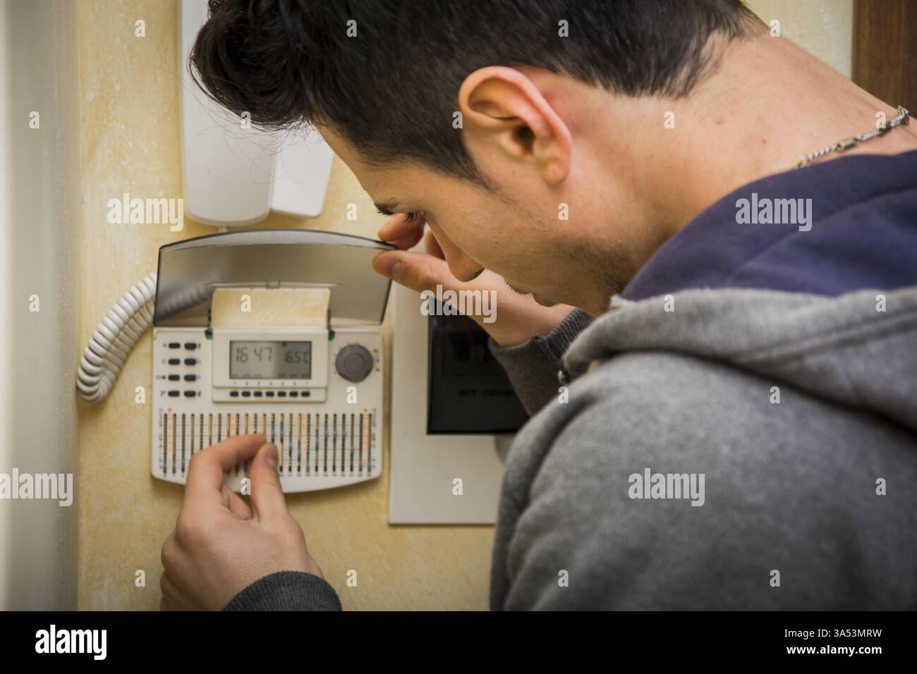 Over the shoulder close up view of a young man standing checking the ...