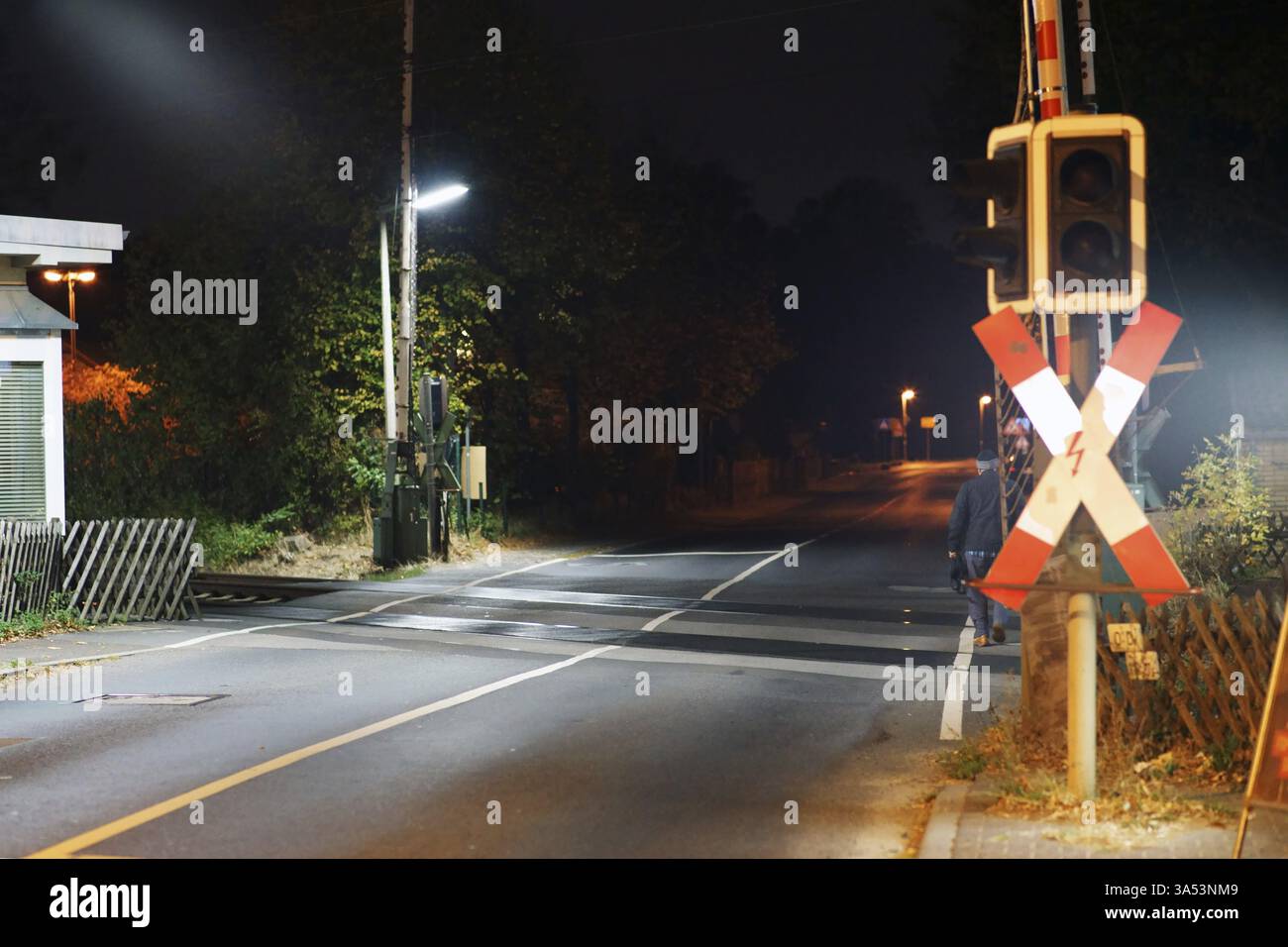 A level crossing with a red signal light at night and in the dark Stock ...