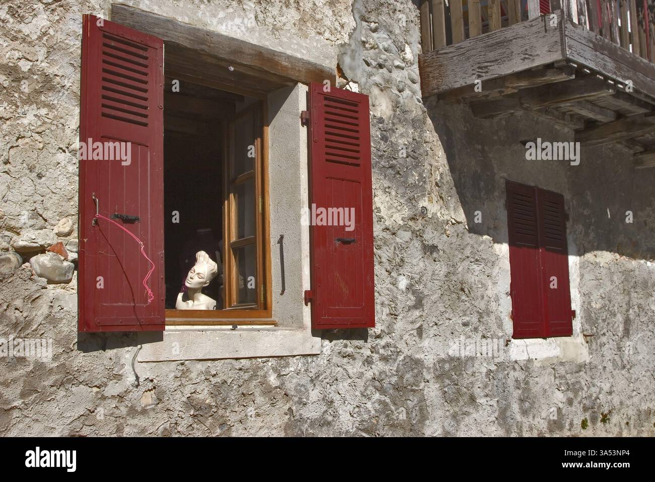 A head of a doll of a dummy in a window of the ancient stone house ...