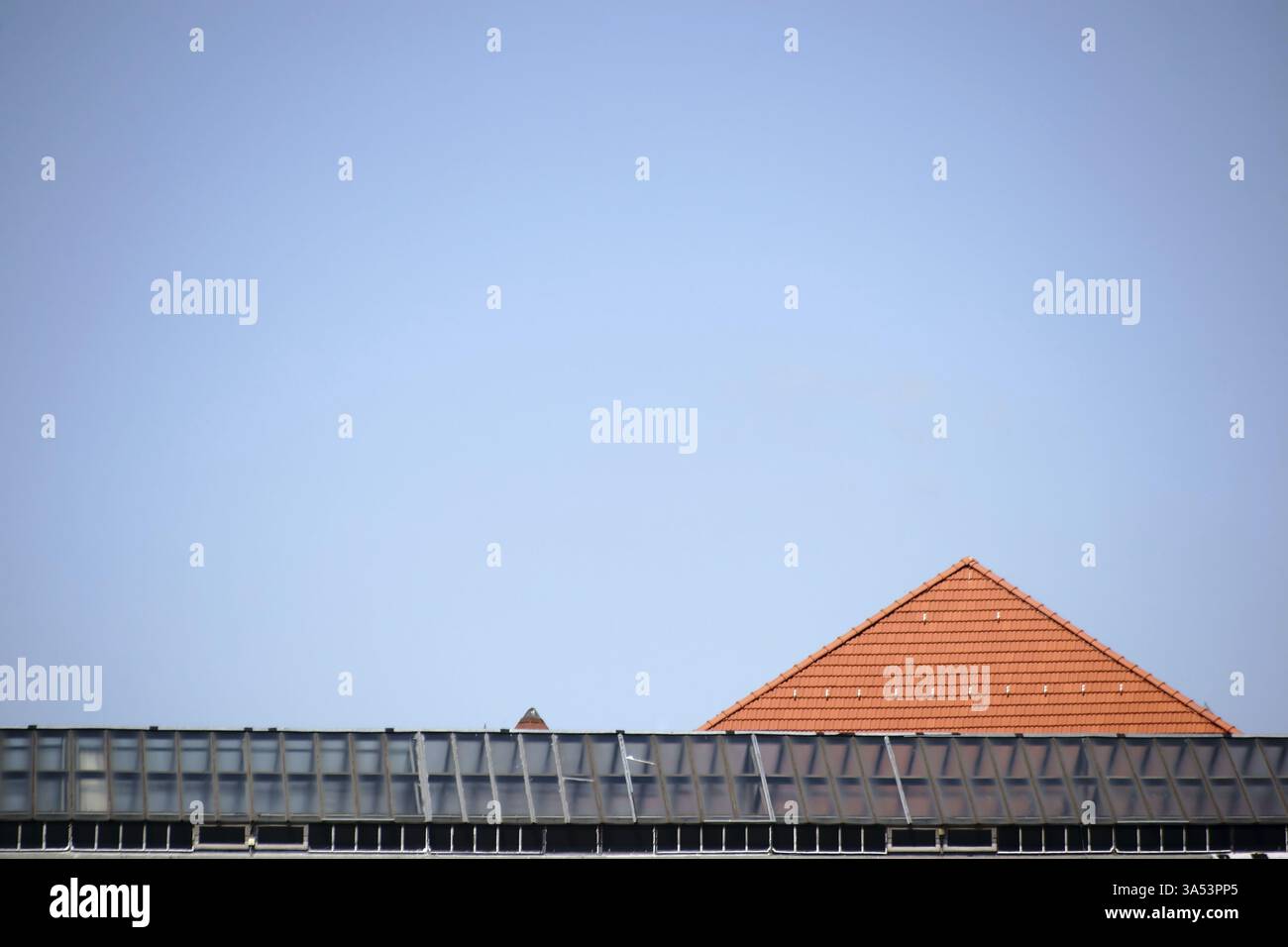 A roof with red tiles and a triangular gable towers over the glass roof ...