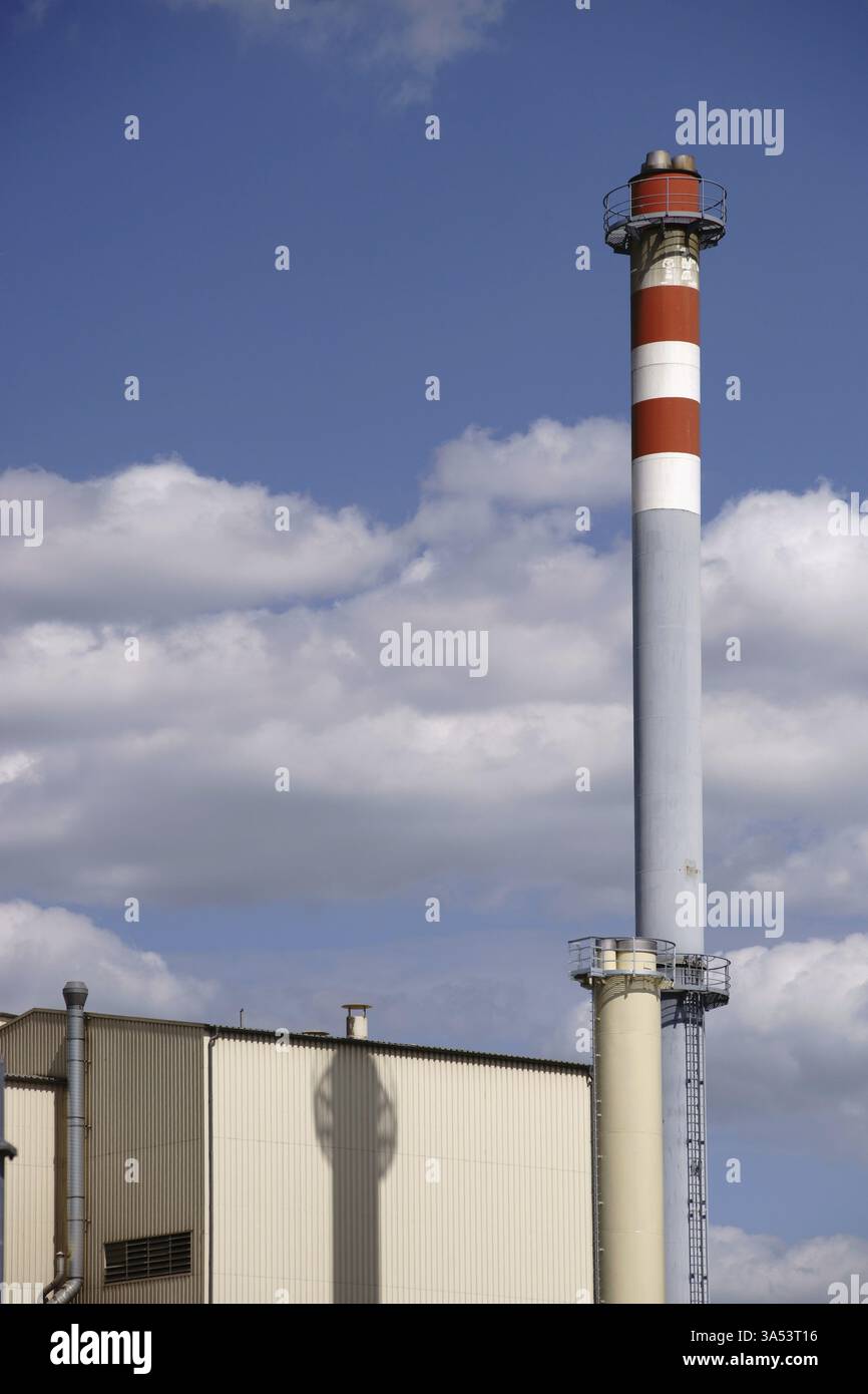 A red and white striped factory chimney next to a factory building ...