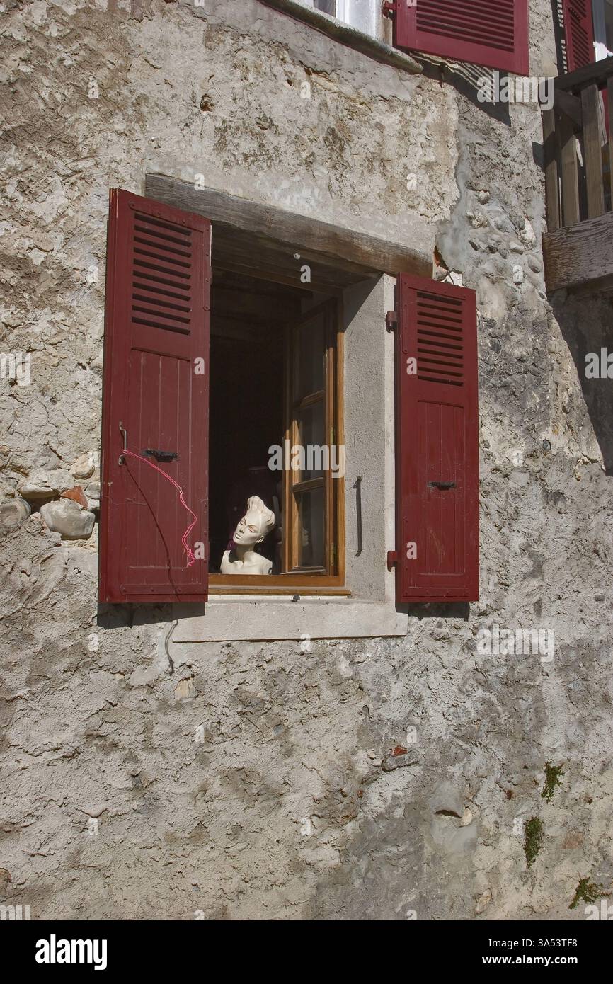 A head of a doll of a dummy in a window of the ancient stone house ...