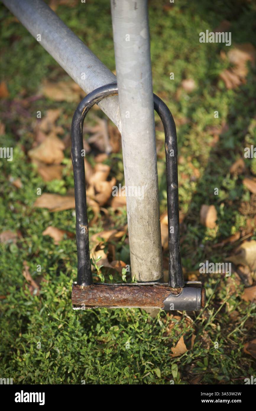 An old rusty bicycle lock left hanging on the tube of a railing Stock ...