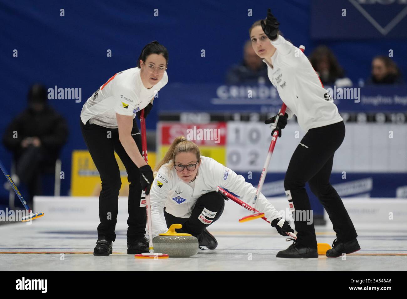 Switzerland's Alina Paetz, center, releases the stone as Switzerland's ...