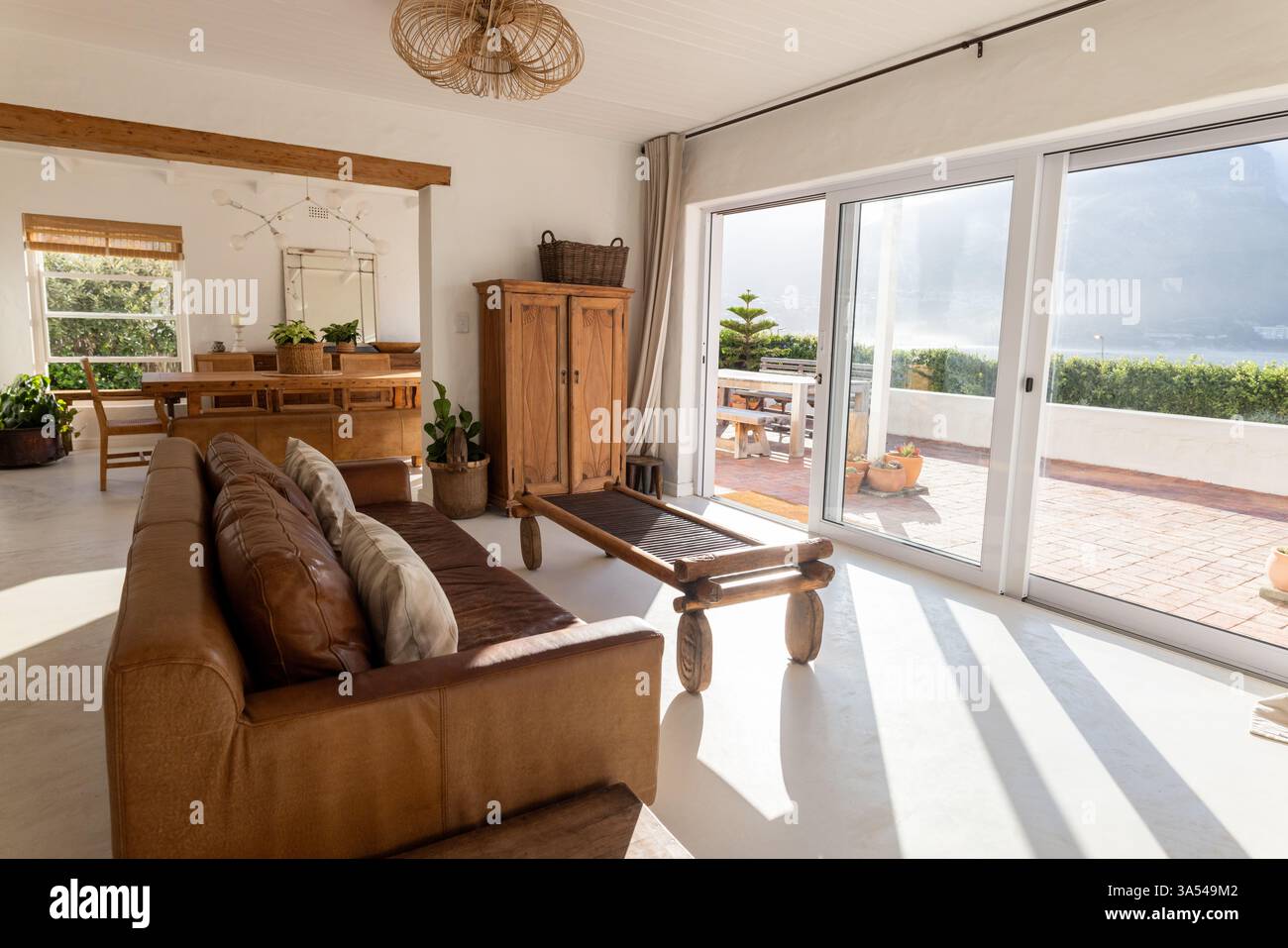 Cozy living room with sunlight streaming through large glass doors to ...
