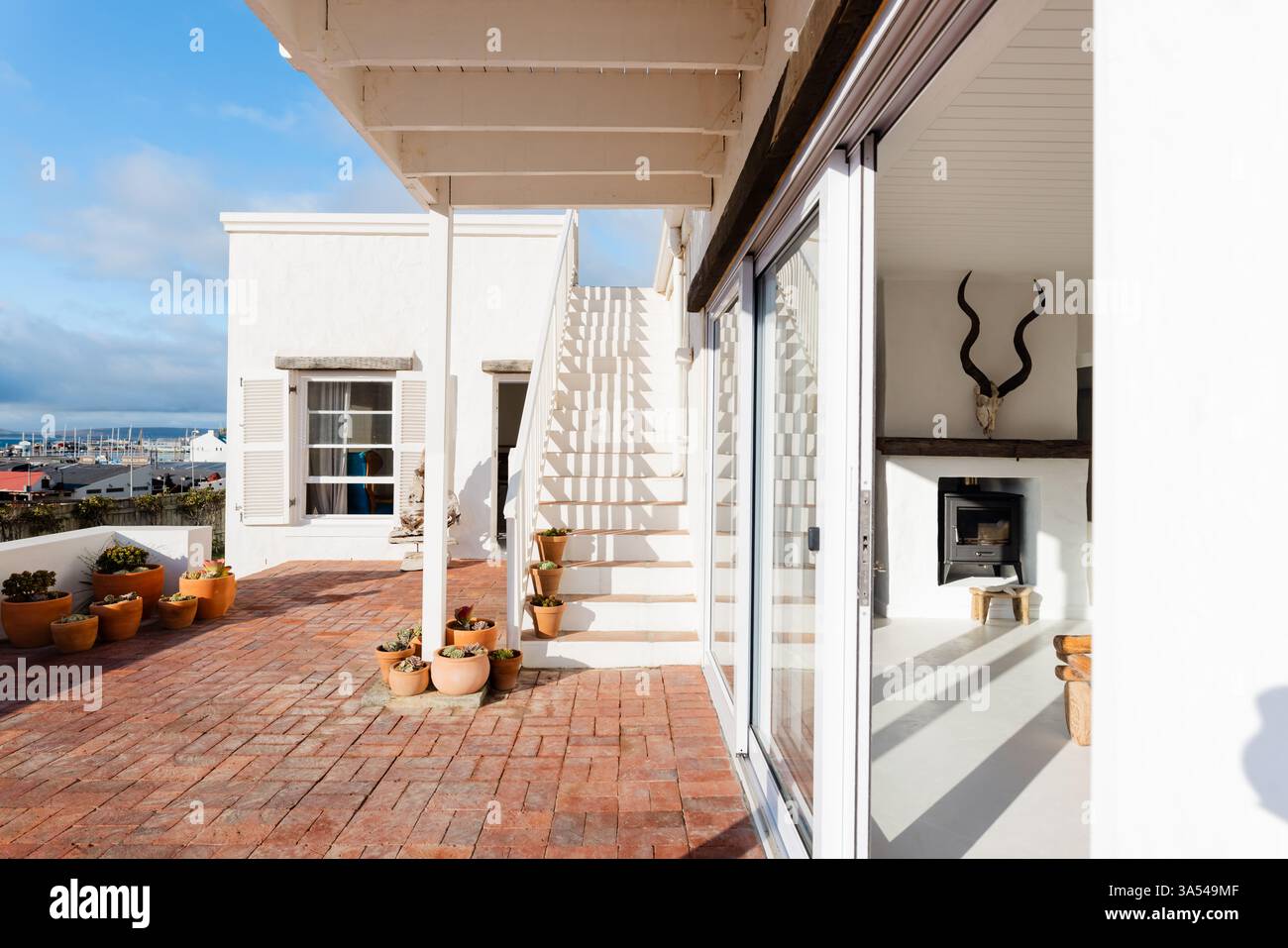 Modern coastal home with sunlit terrace and potted plants, perfect for ...