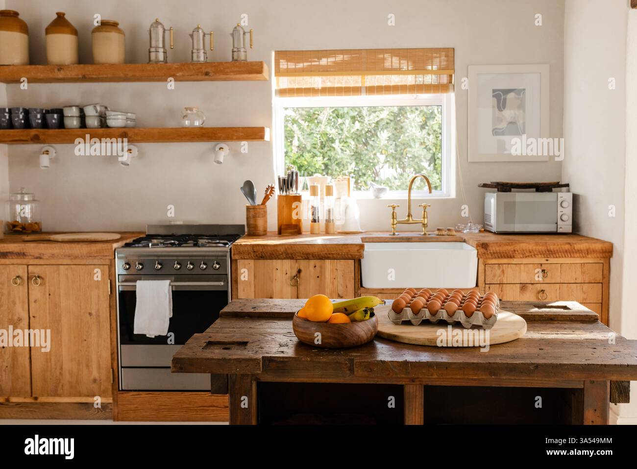 Cozy kitchen with fresh fruit and eggs on rustic wooden table, sunlight ...