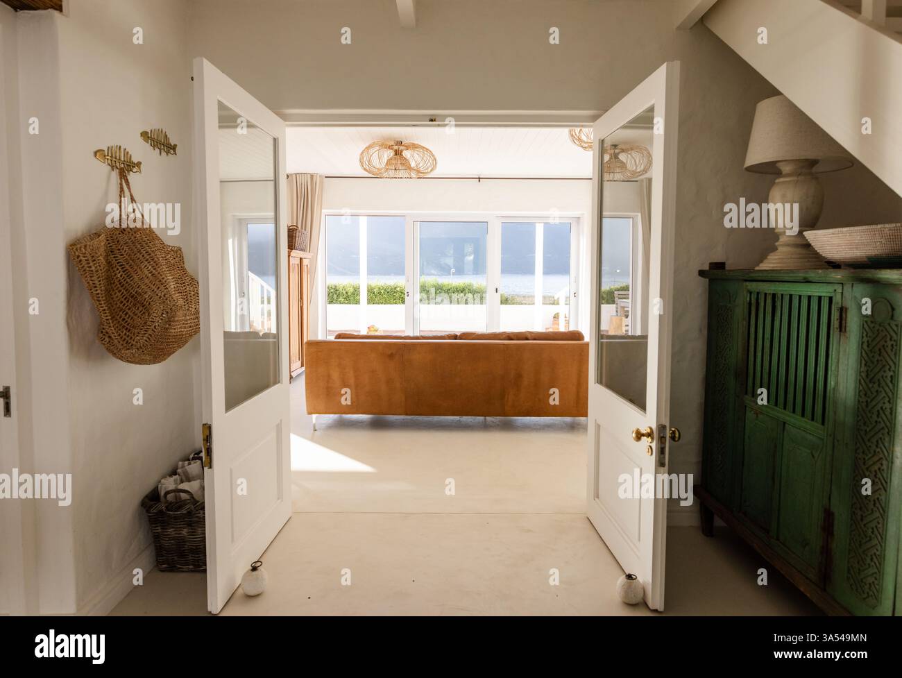 Cozy beach house living room with ocean view through open double doors ...