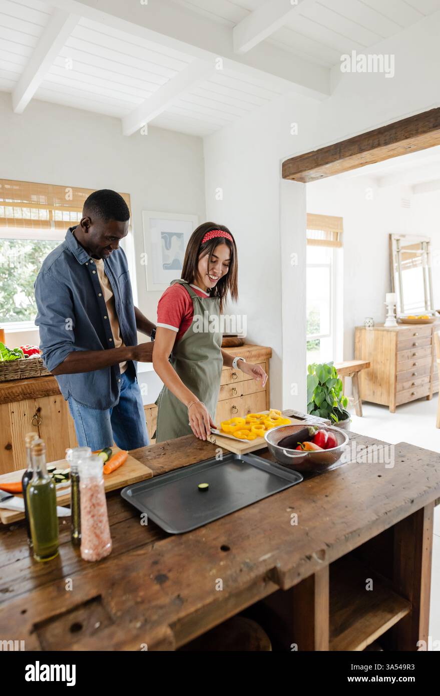 Preparing fresh vegetables, Diverse couple cooking together in cozy ...