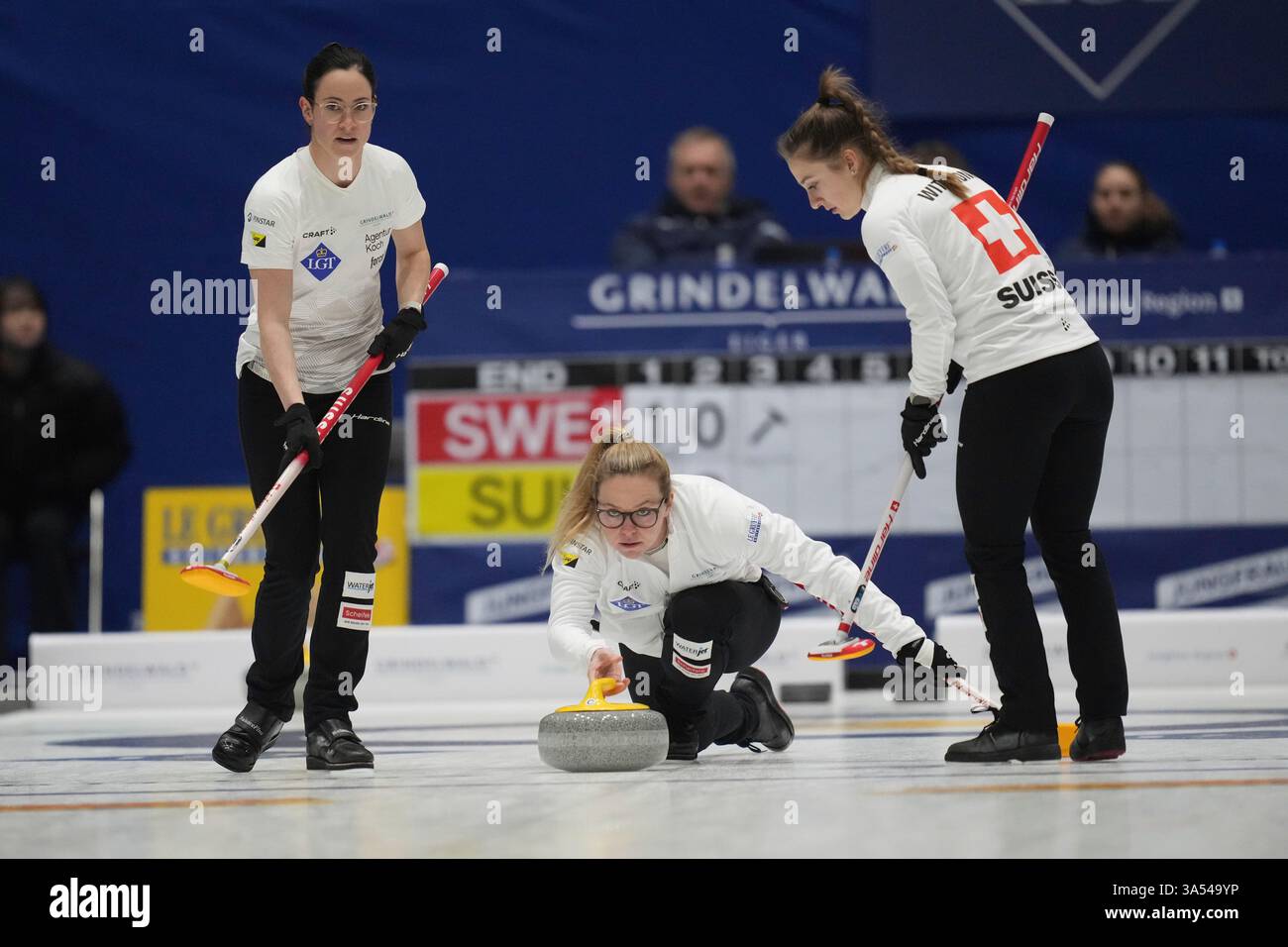 Switzerland's Alina Paetz, center, releases the stone as Switzerland's ...