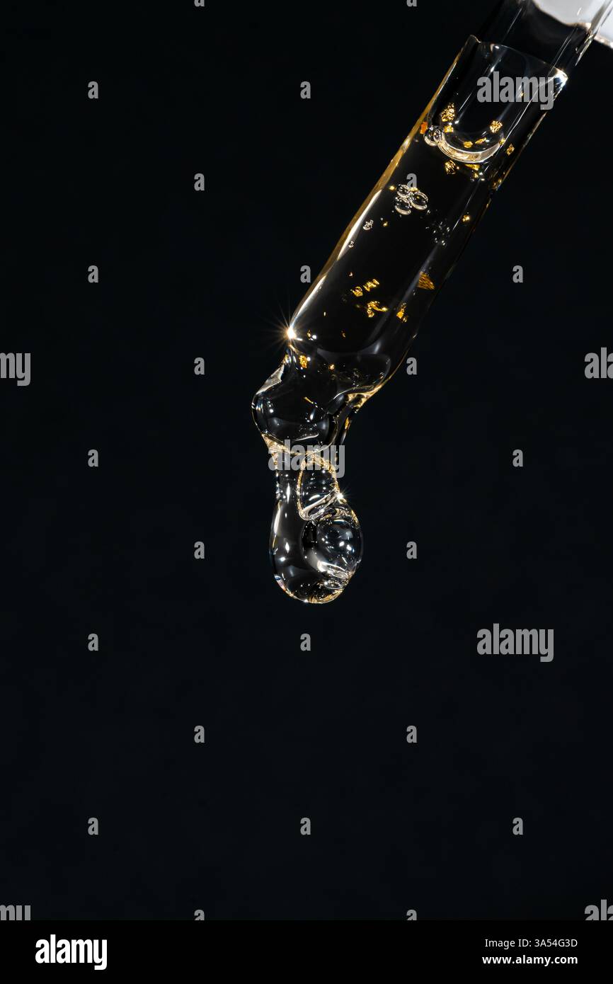 Liquid serum and dropper on a black background macro. 24k gold Serum ...