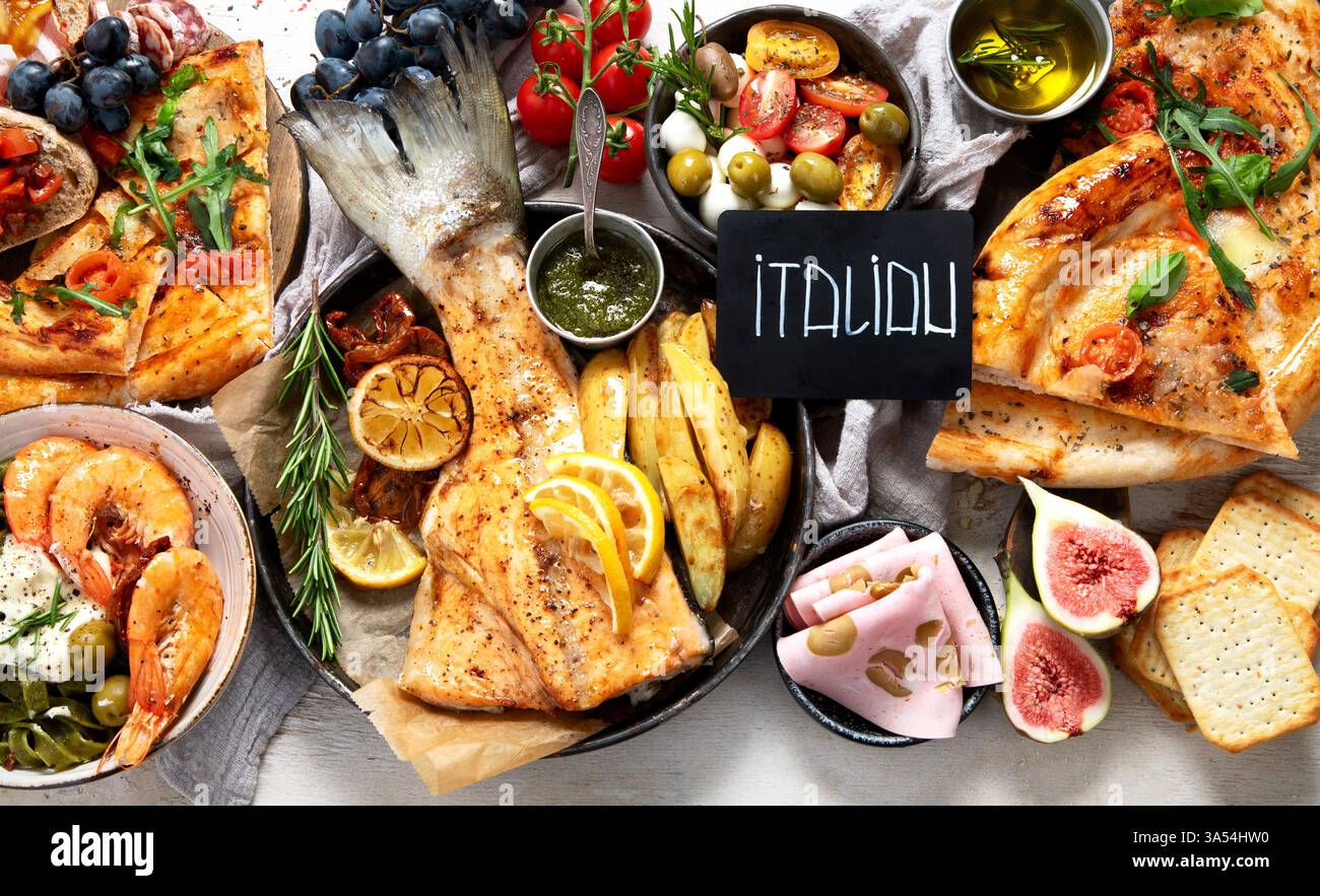 Full table of italian meals on plates and board - Pizza, pasta, salami ...