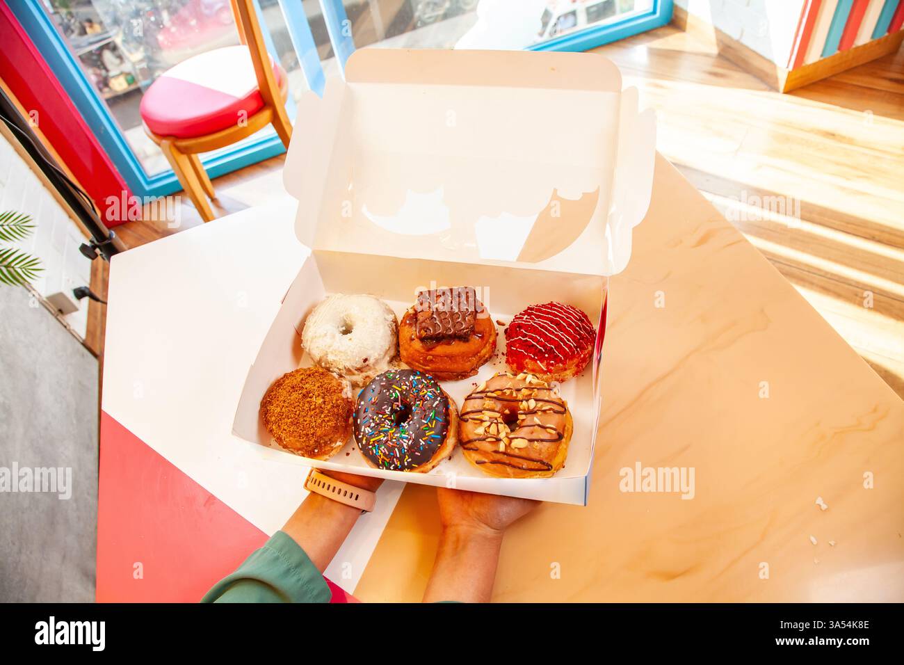 Hand holding doughnut box of assorted mixed hand made brioche donuts Stock Photo - Alamy