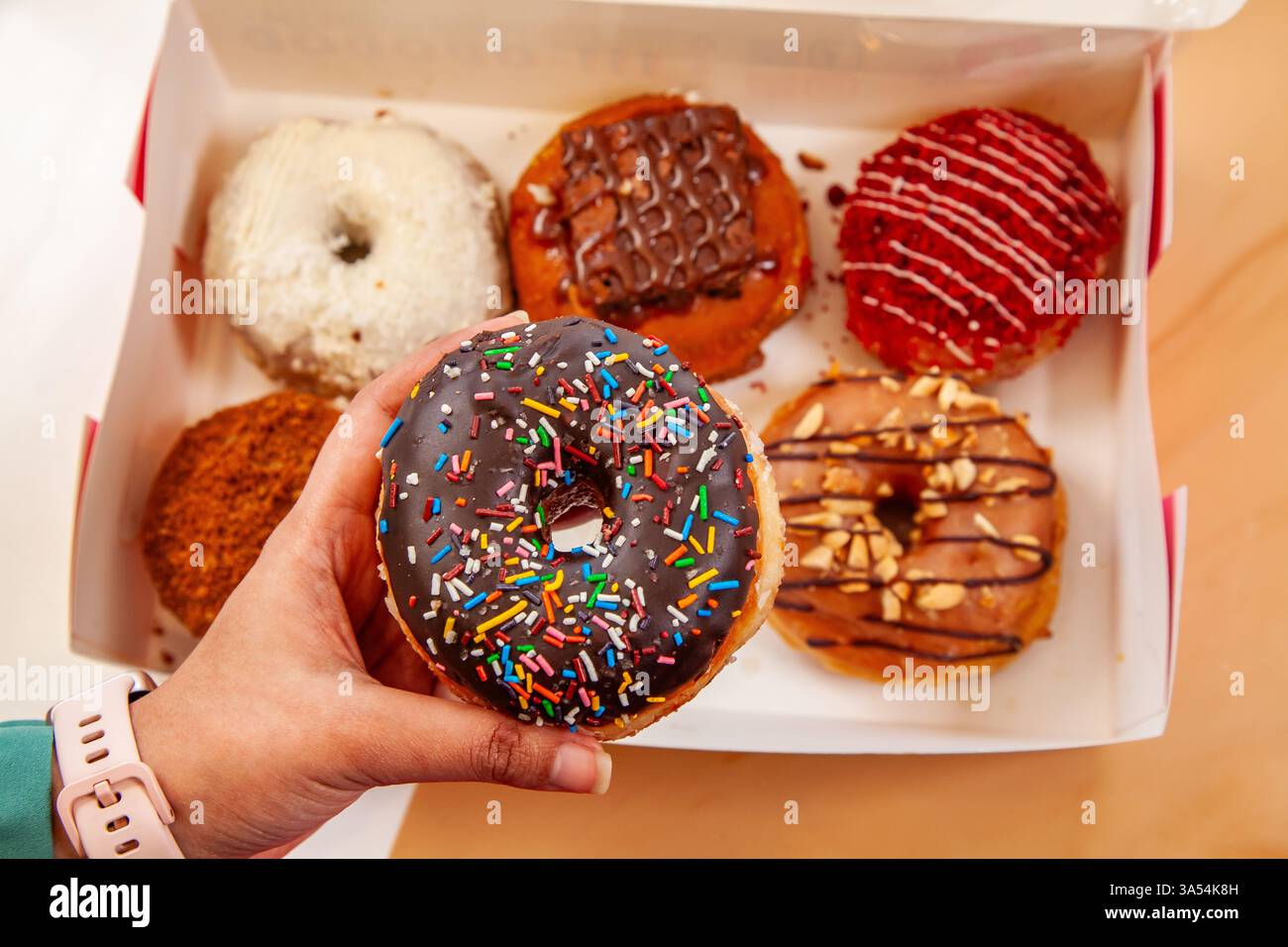 Hand holding doughnut box of assorted mixed hand made brioche donuts ...