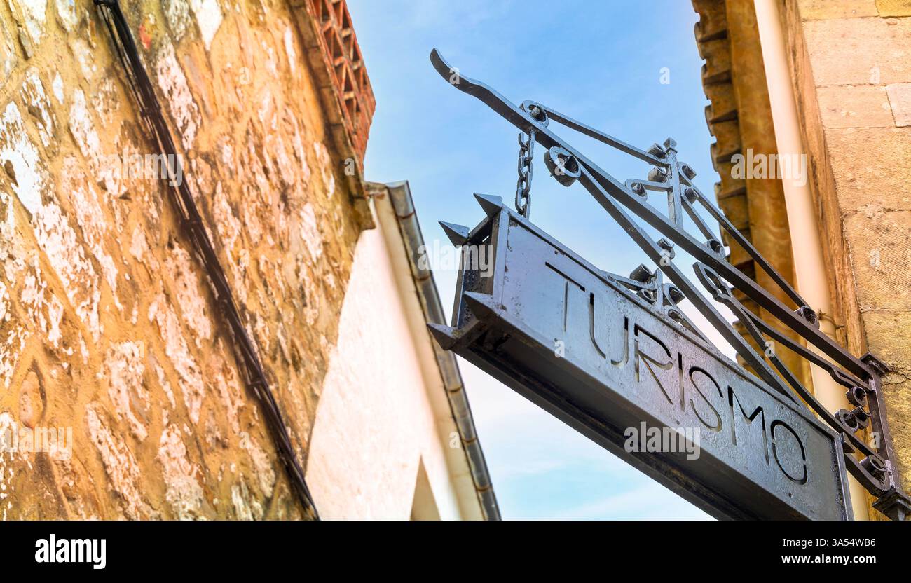 A sign hanging from a building that says Turismo. The sign is made in ...