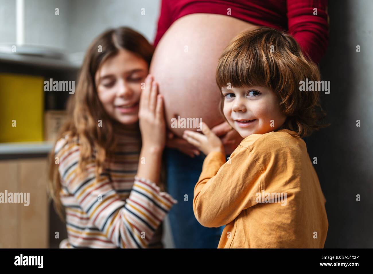 Lovely children touching mother's pregnant belly. Happy little siblings ...