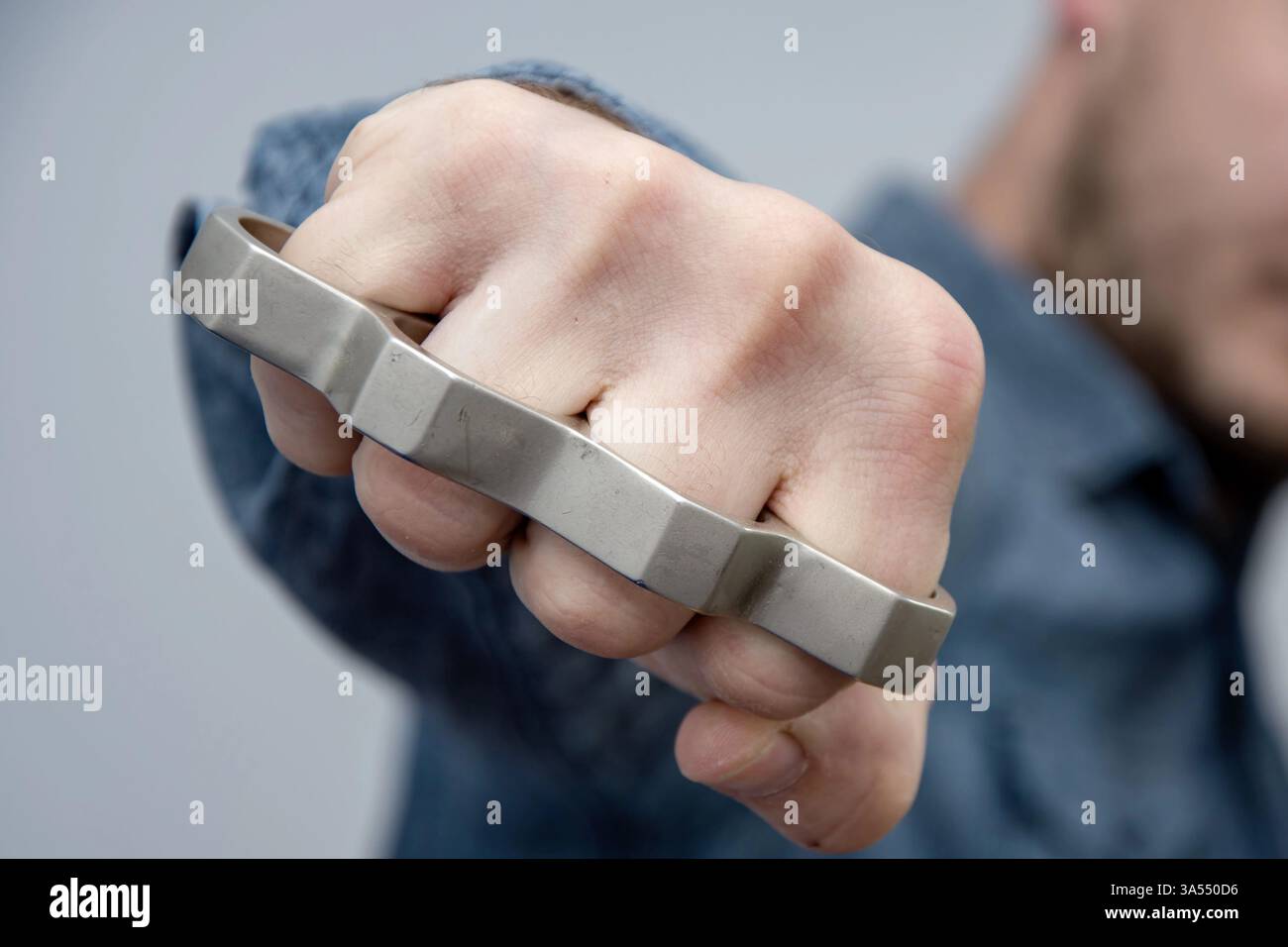 Man strikes brass knuckles on a light background, a prohibited weapon ...