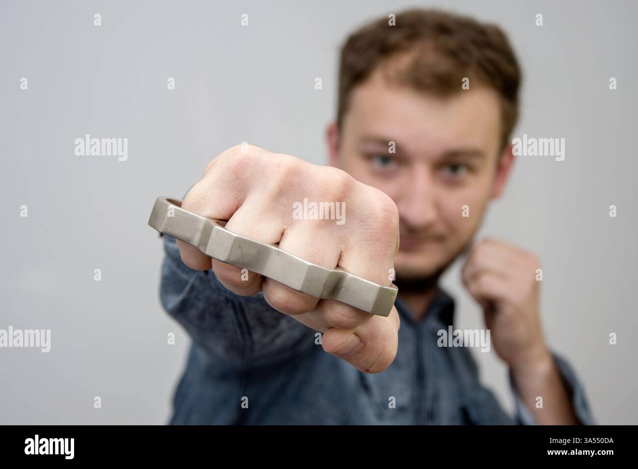 Man strikes brass knuckles on a light background, a prohibited weapon ...
