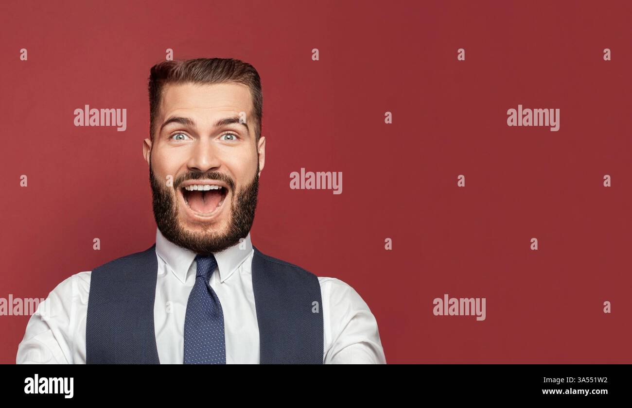 Young man with a surprised happy expression won on red studio ...