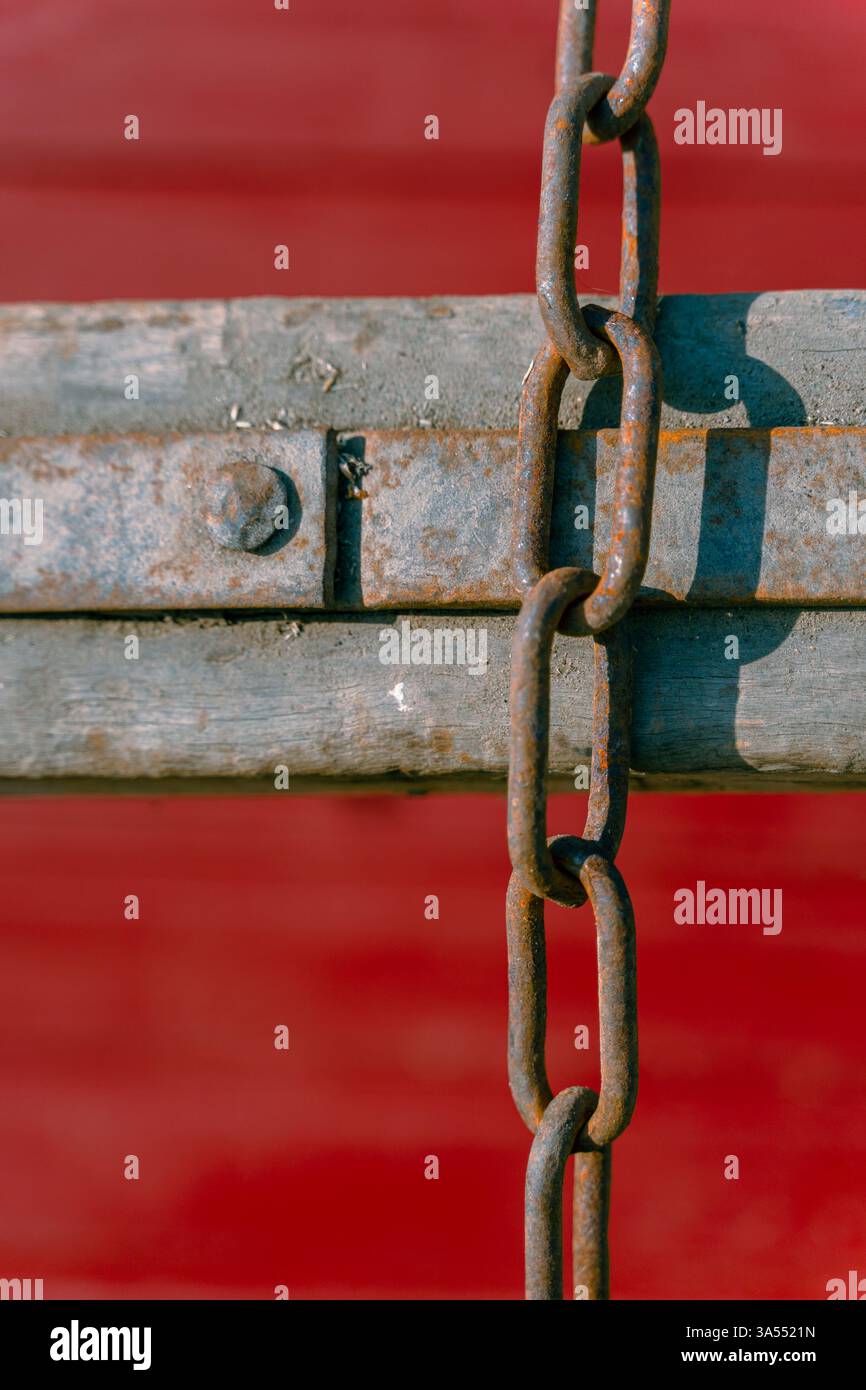old rusty chain of a timber sledge in front of a red wooden gate Stock ...