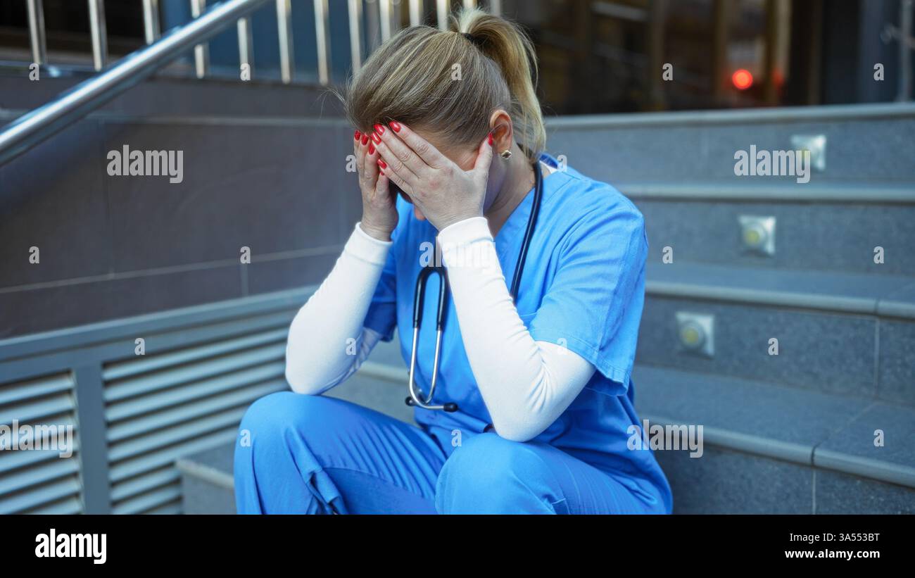 Nurse sitting on hospital steps looking stressed outdoors with hands ...