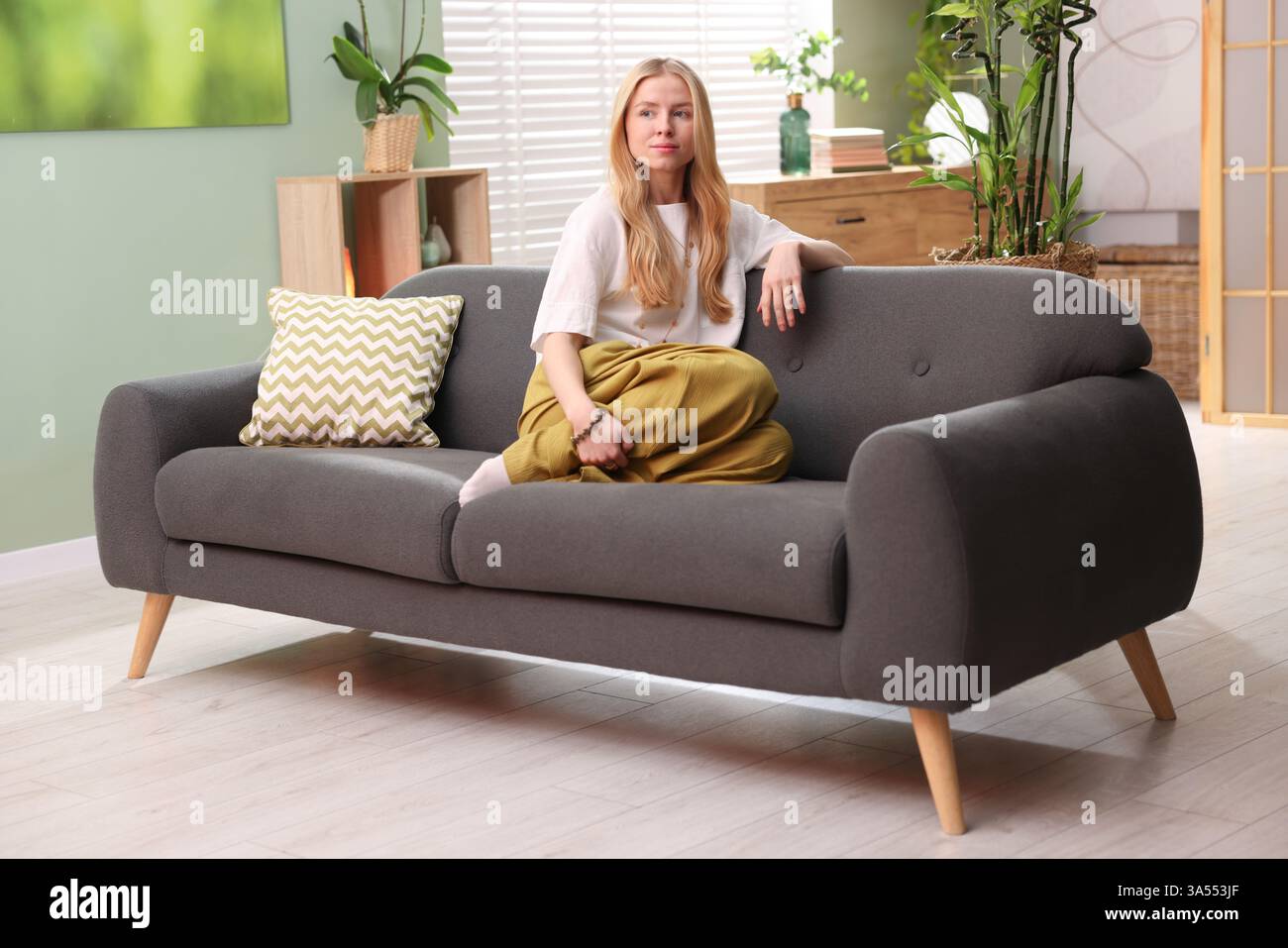 Feng shui. Young woman sitting on couch at home Stock Photo - Alamy