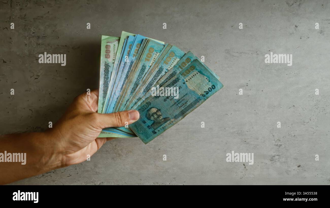 Hand holding bangladeshi taka currency notes against a concrete ...