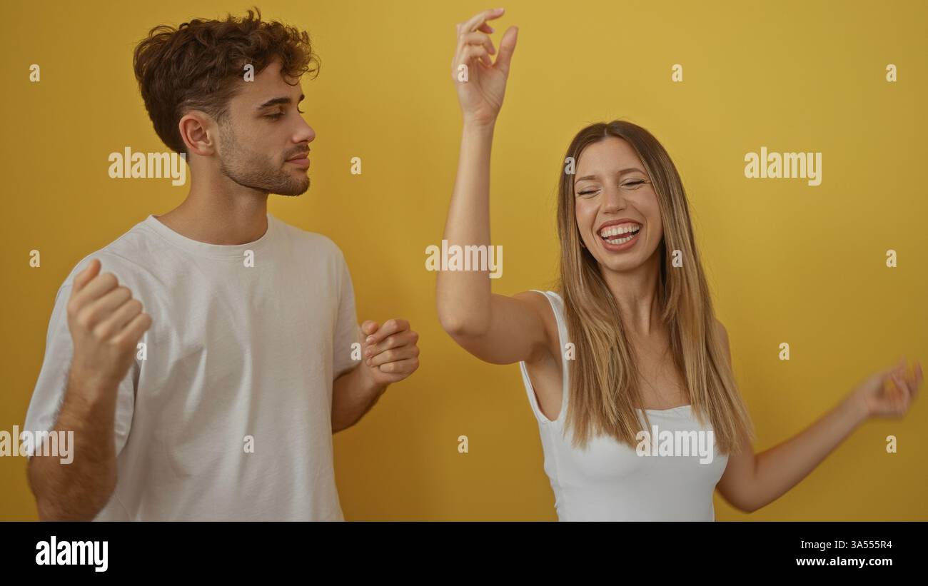 Man and woman dancing happily together against a vibrant yellow ...