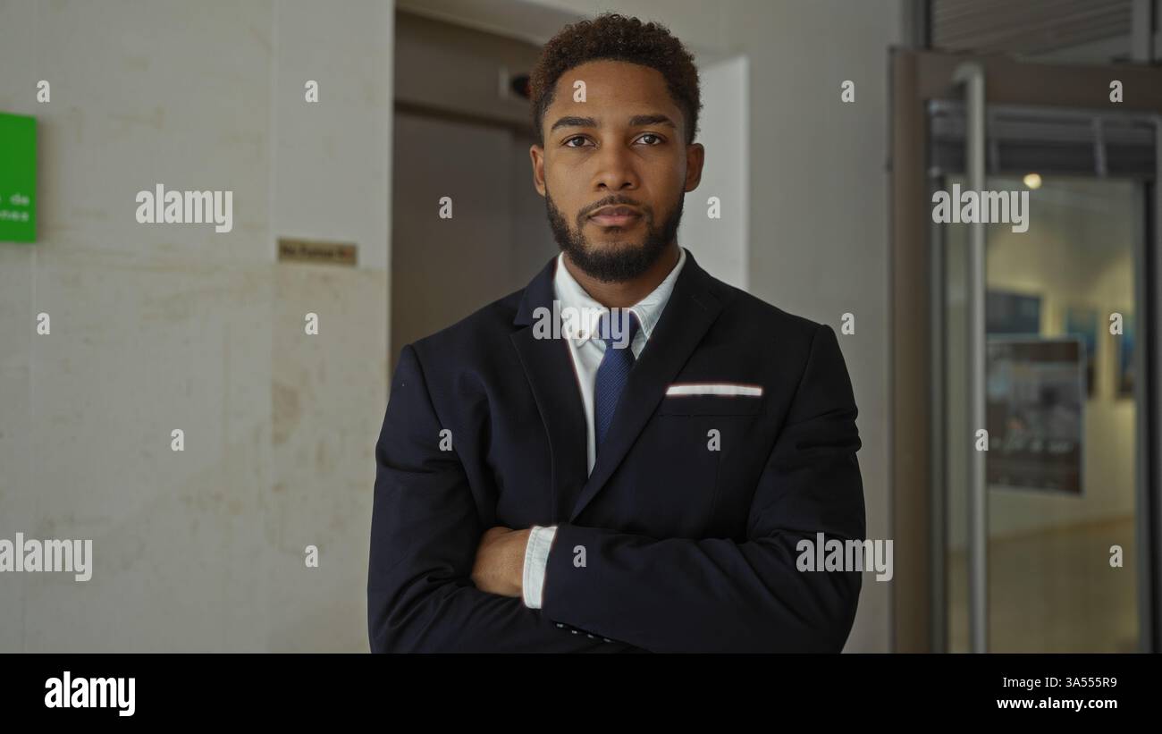 Confident young man in a formal suit standing with crossed arms in an ...