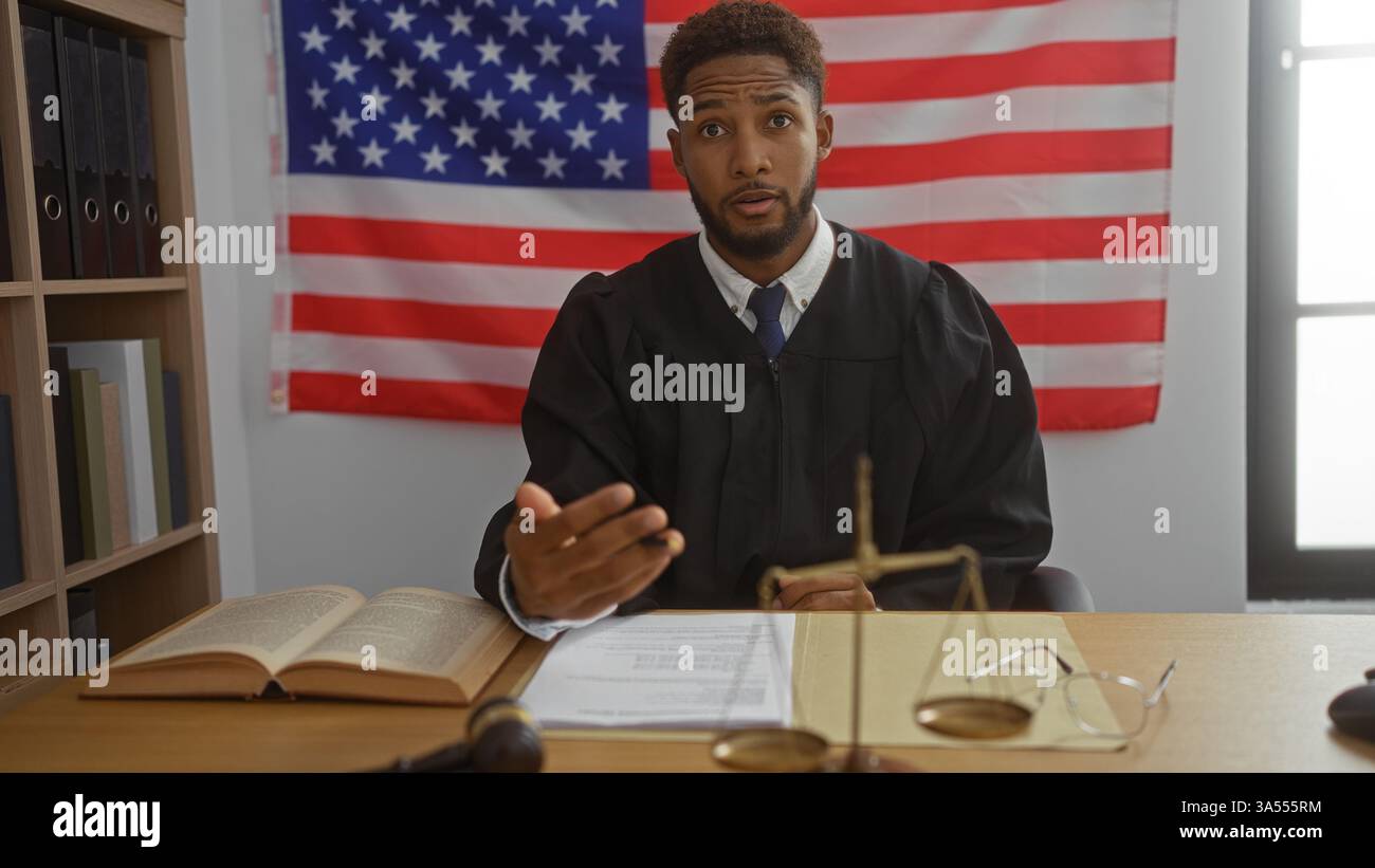 Young man in courtroom wearing judge's robes, sitting at a desk with ...