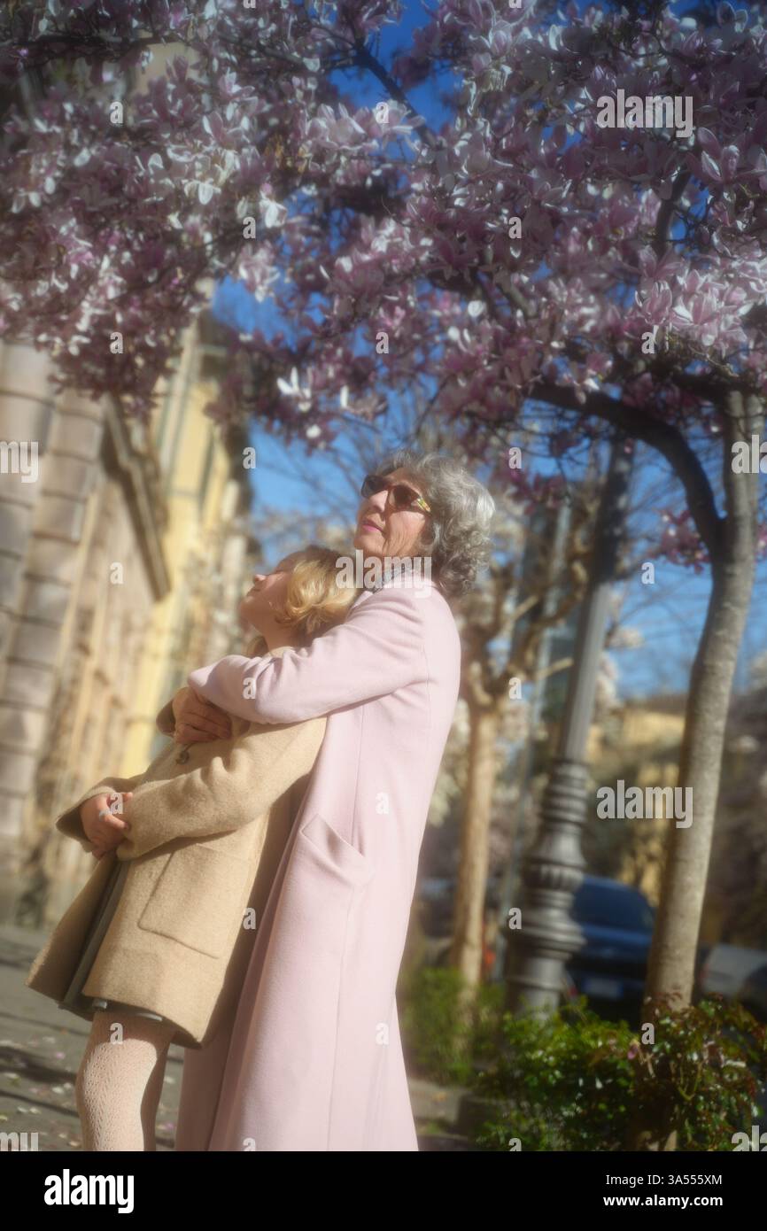 Grandmother and granddaughter share a tender embrace beneath a blooming ...