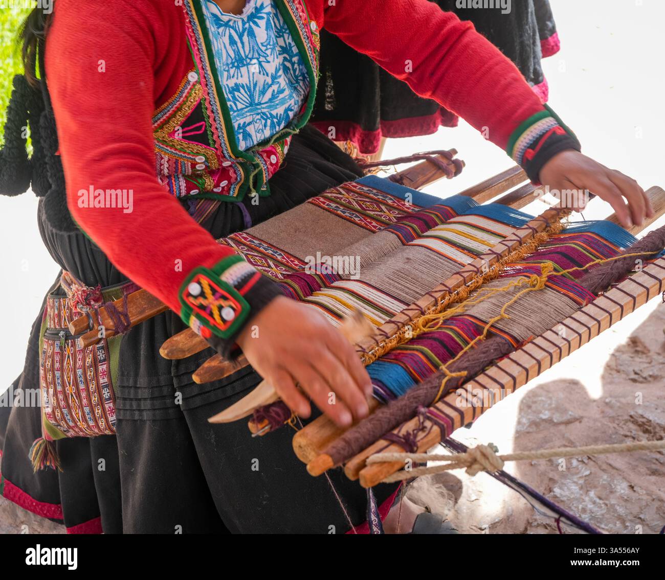 An artisan near Cusco, Peru, weaves a traditional textile using a ...