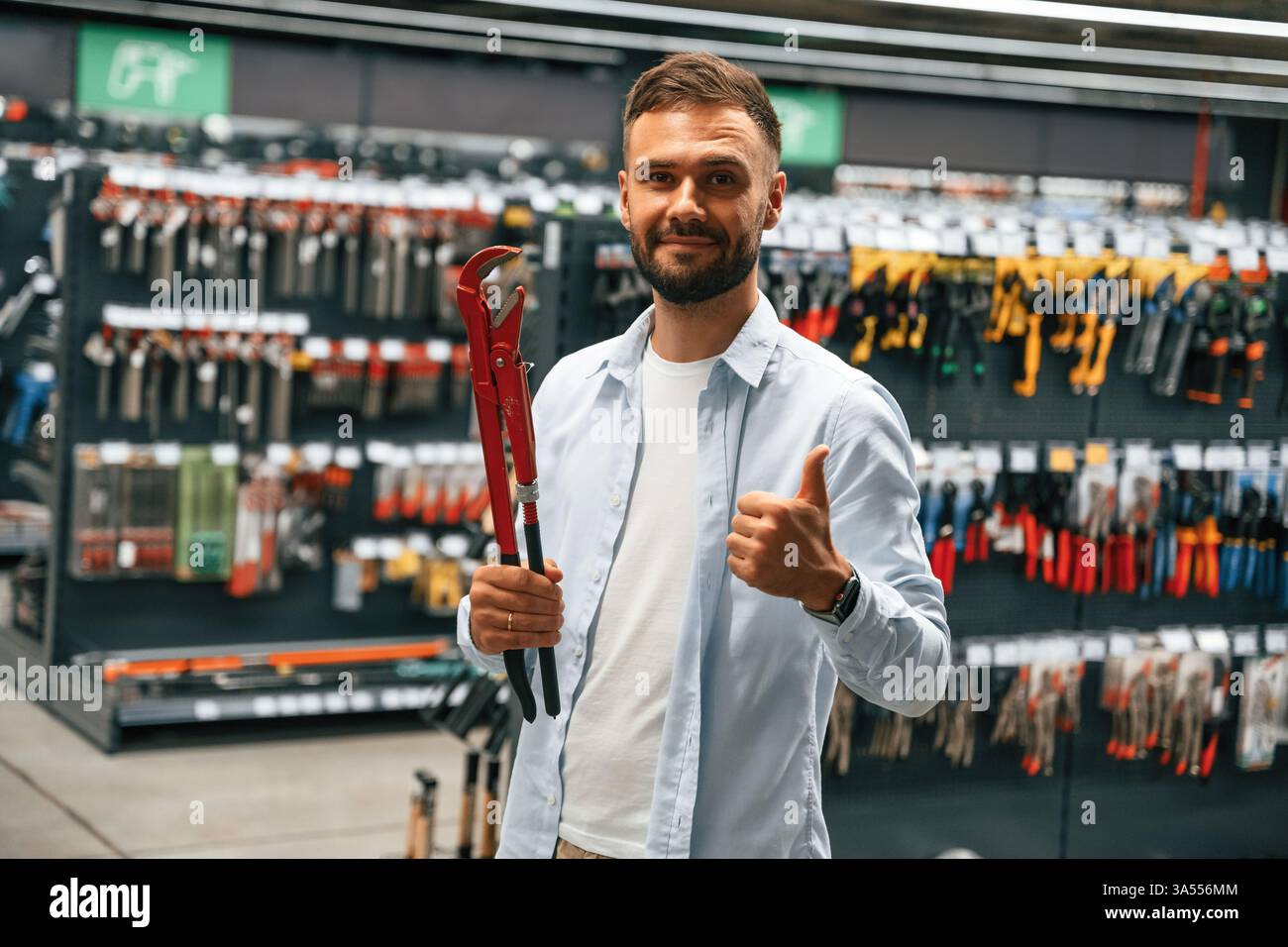 Red plumbing wrench. Man is in the hardware shop Stock Photo - Alamy