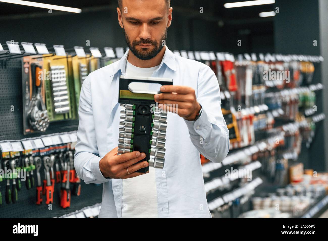 Selecting the new equipment. Man is in the hardware shop Stock Photo - Alamy