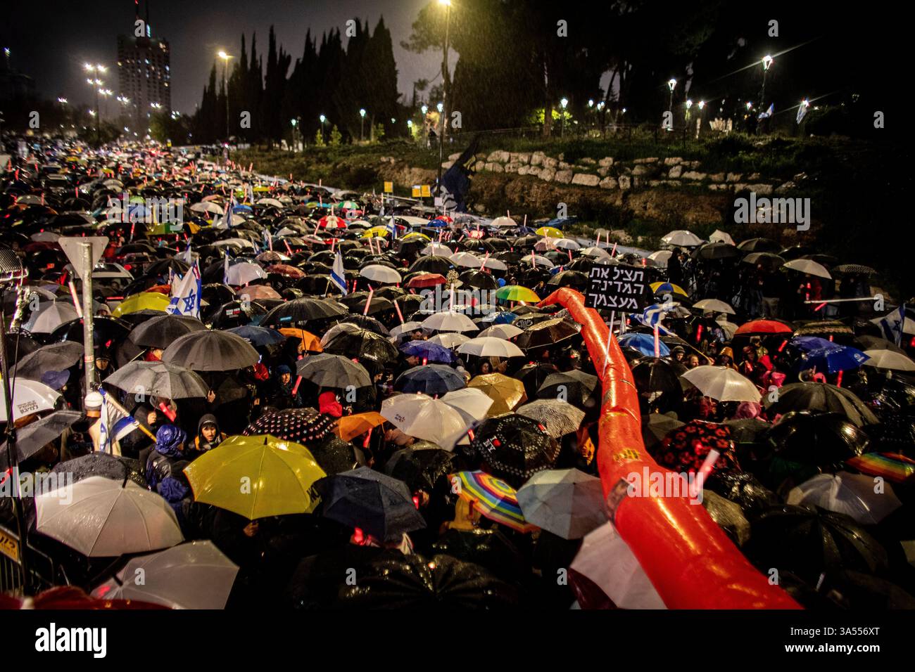 Israeli demonstrators stand in poring rain as they protest outside the ...