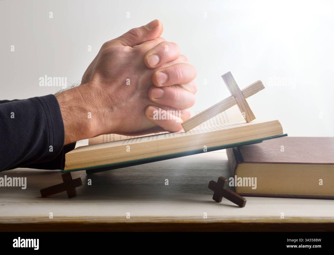Catholic person praying with hands with fingers crossed over a bible on ...