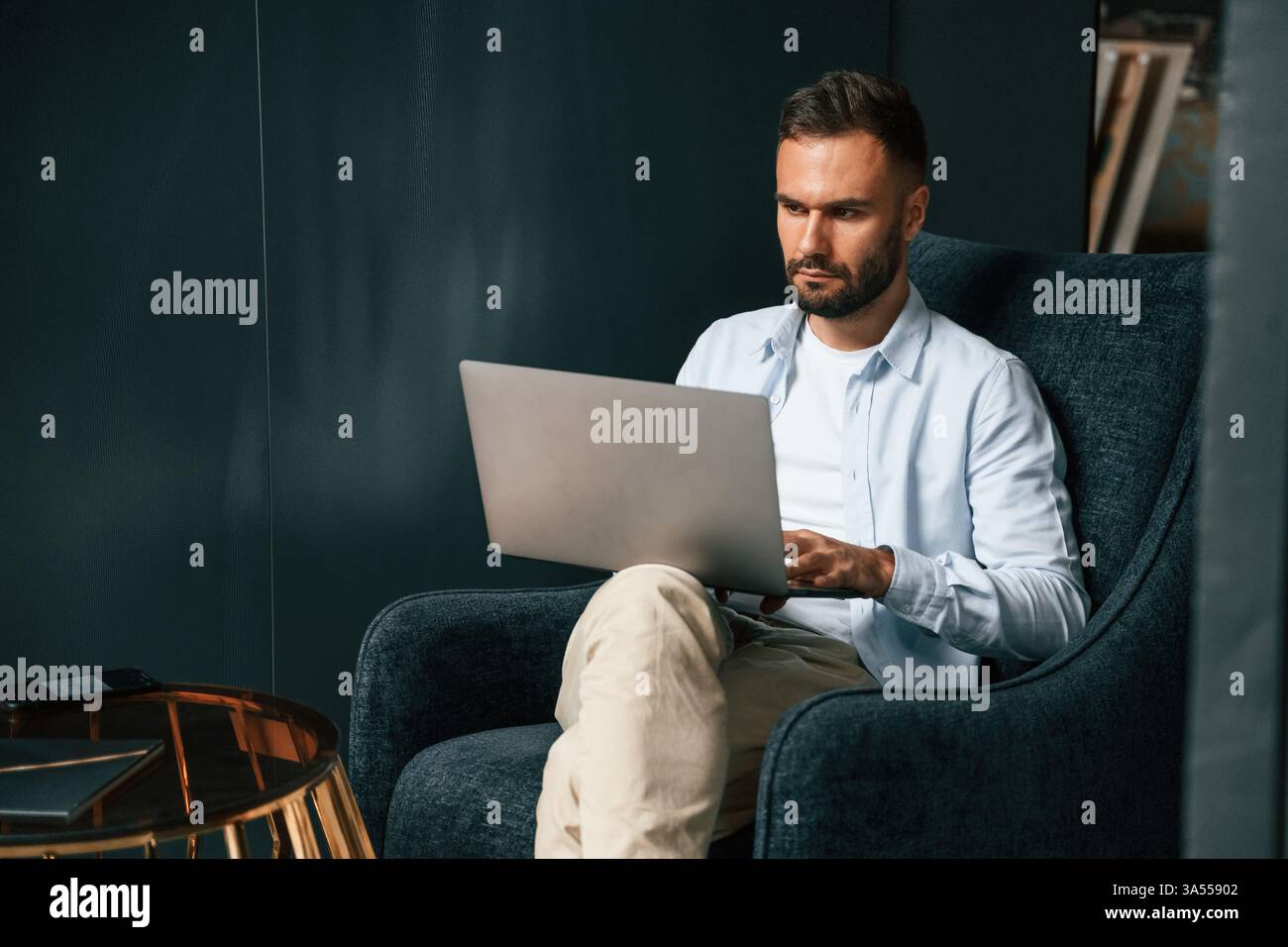 Focused, confident. Businessman is sitting and working by using laptop ...
