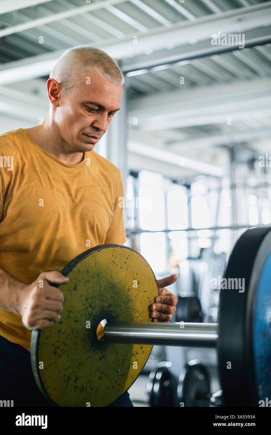 Senior Man Loading Weight Plates onto a Barbell in a Gym Stock Photo ...